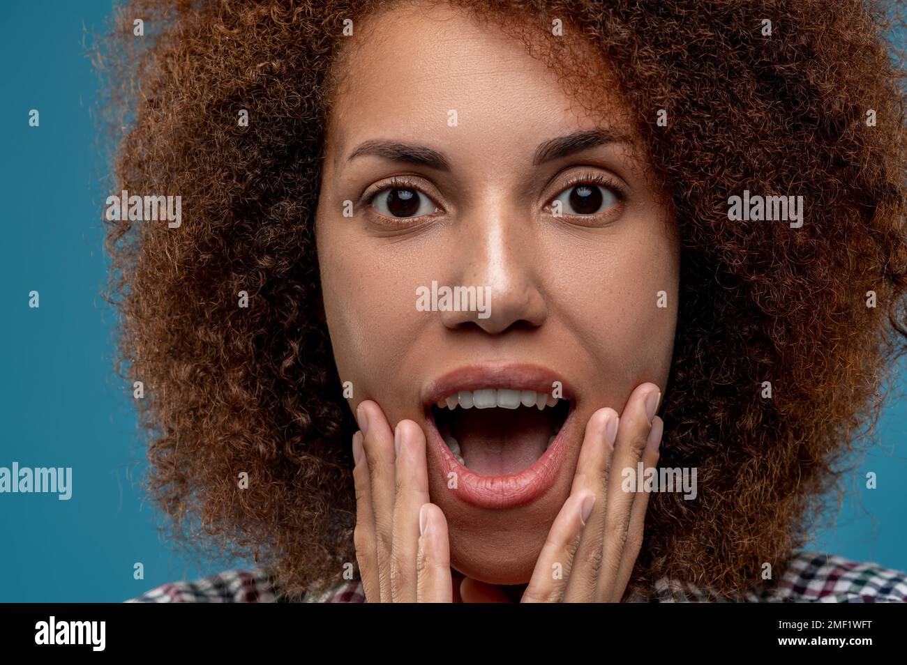Curly-haired young woman looking contented and smiling Stock Photo - Alamy