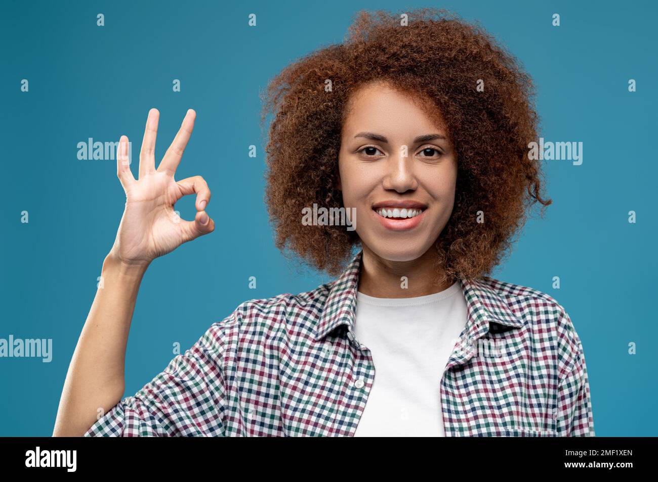 Young smiling woman showing ok sign and looking contented Stock Photo ...