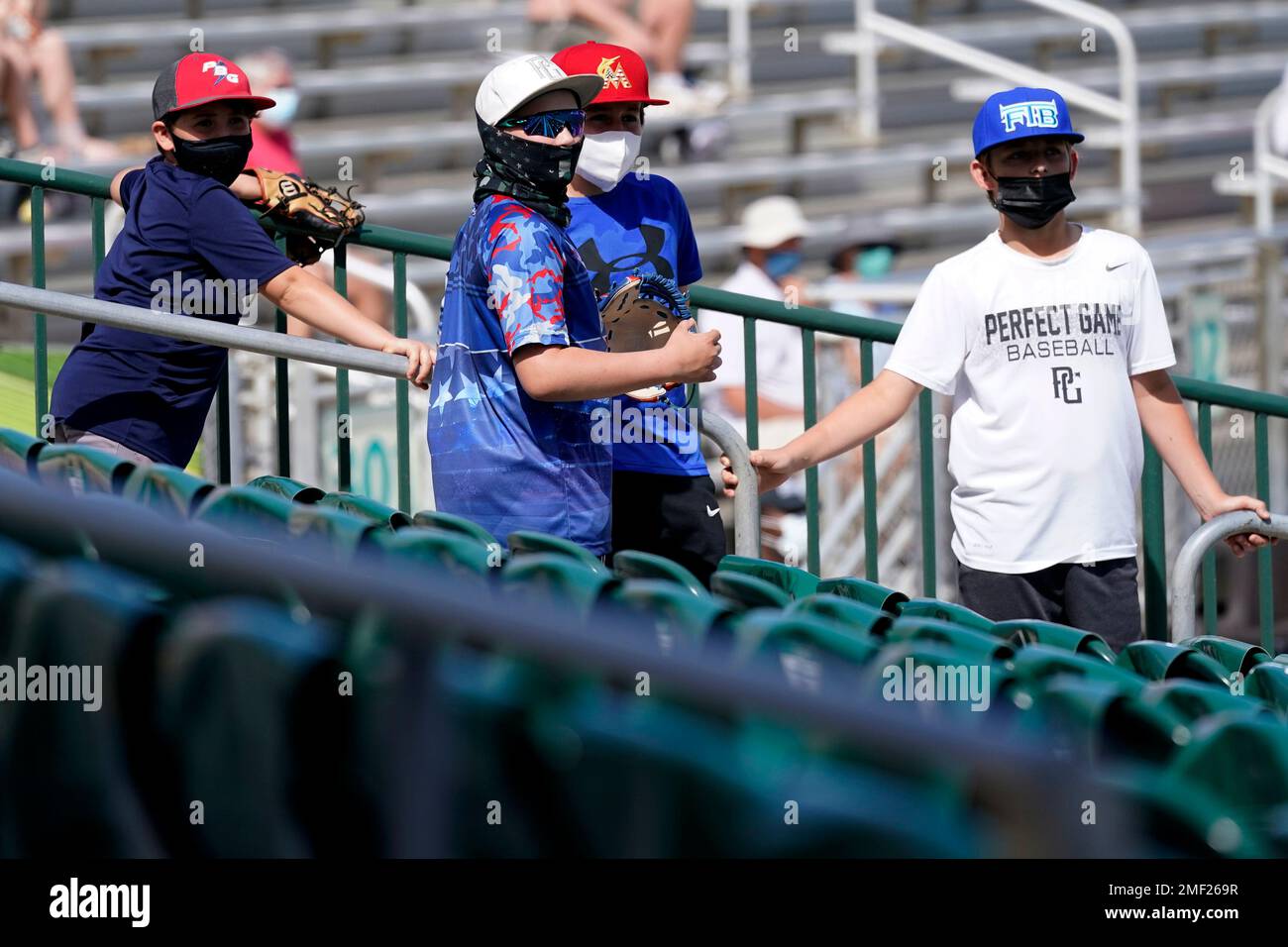 Young baseball fans wearing face masks wait in the outfield for foul ...