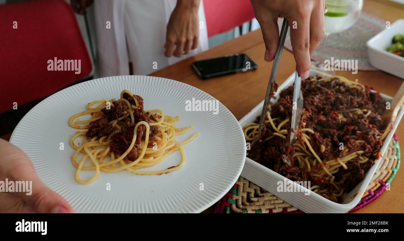 Closeup hand serving spaghetti pasta into plate for meal Stock Photo ...