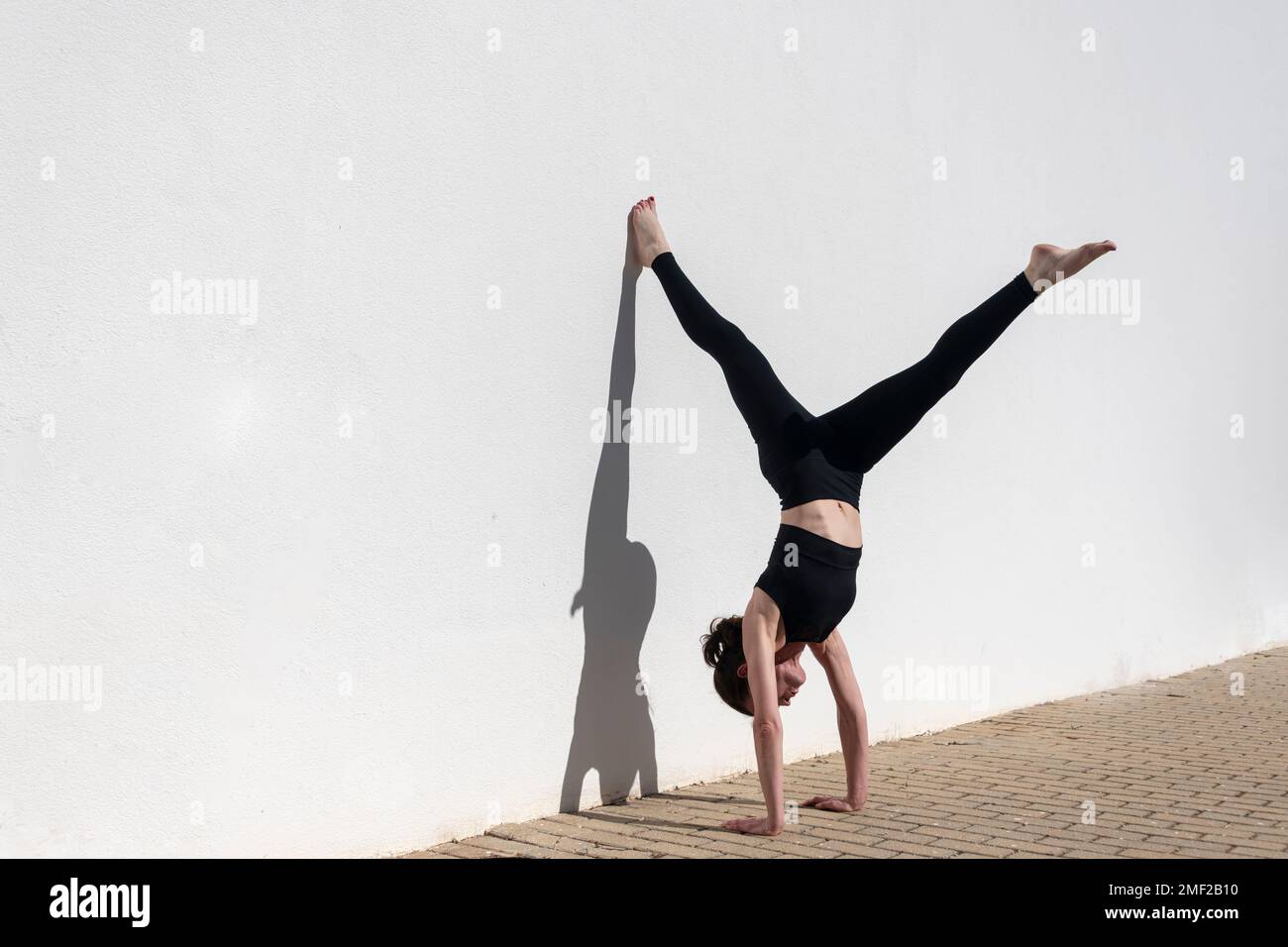 Woman doing a handstand against a white wall in the sun Stock Photo - Alamy