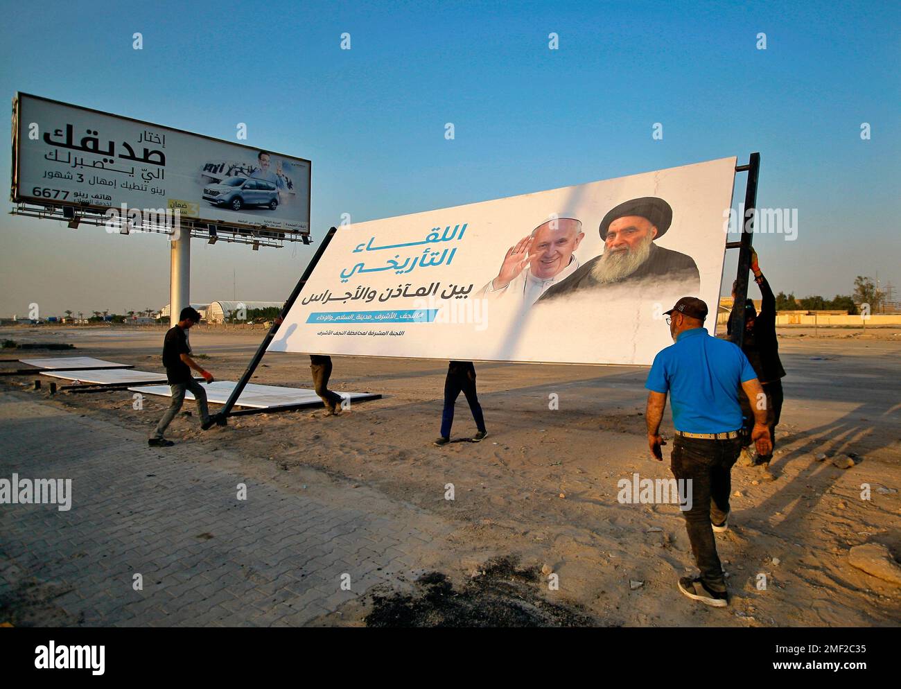 Iraqis put up a billboard announcing the upcoming visit of Pope Francis ...
