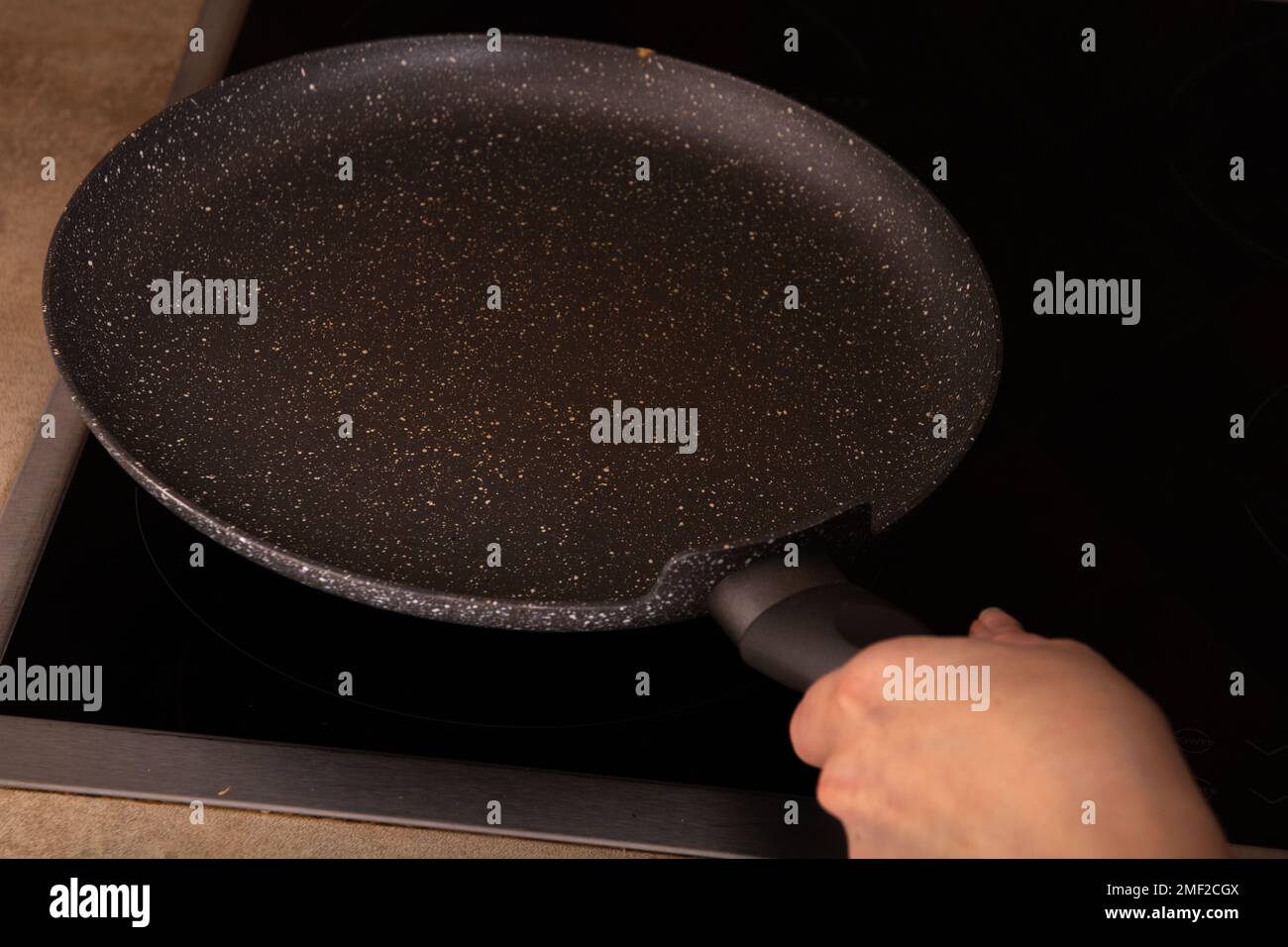 photo of an empty frying pan in hand on an empty stove Stock Photo - Alamy