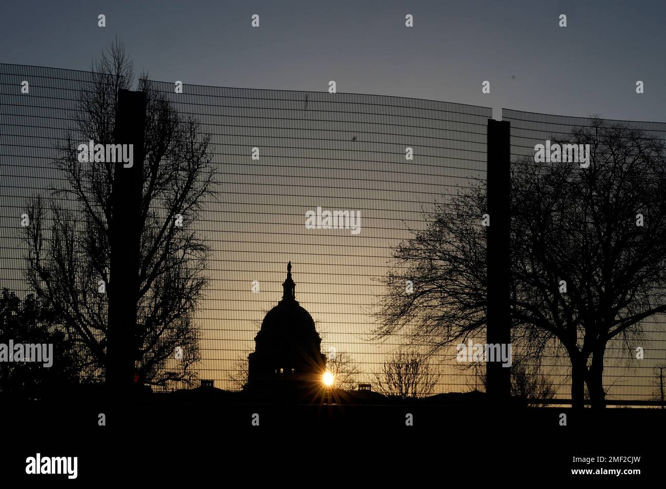The Capitol dome is seen beyond a perimeter security fence at sunrise ...