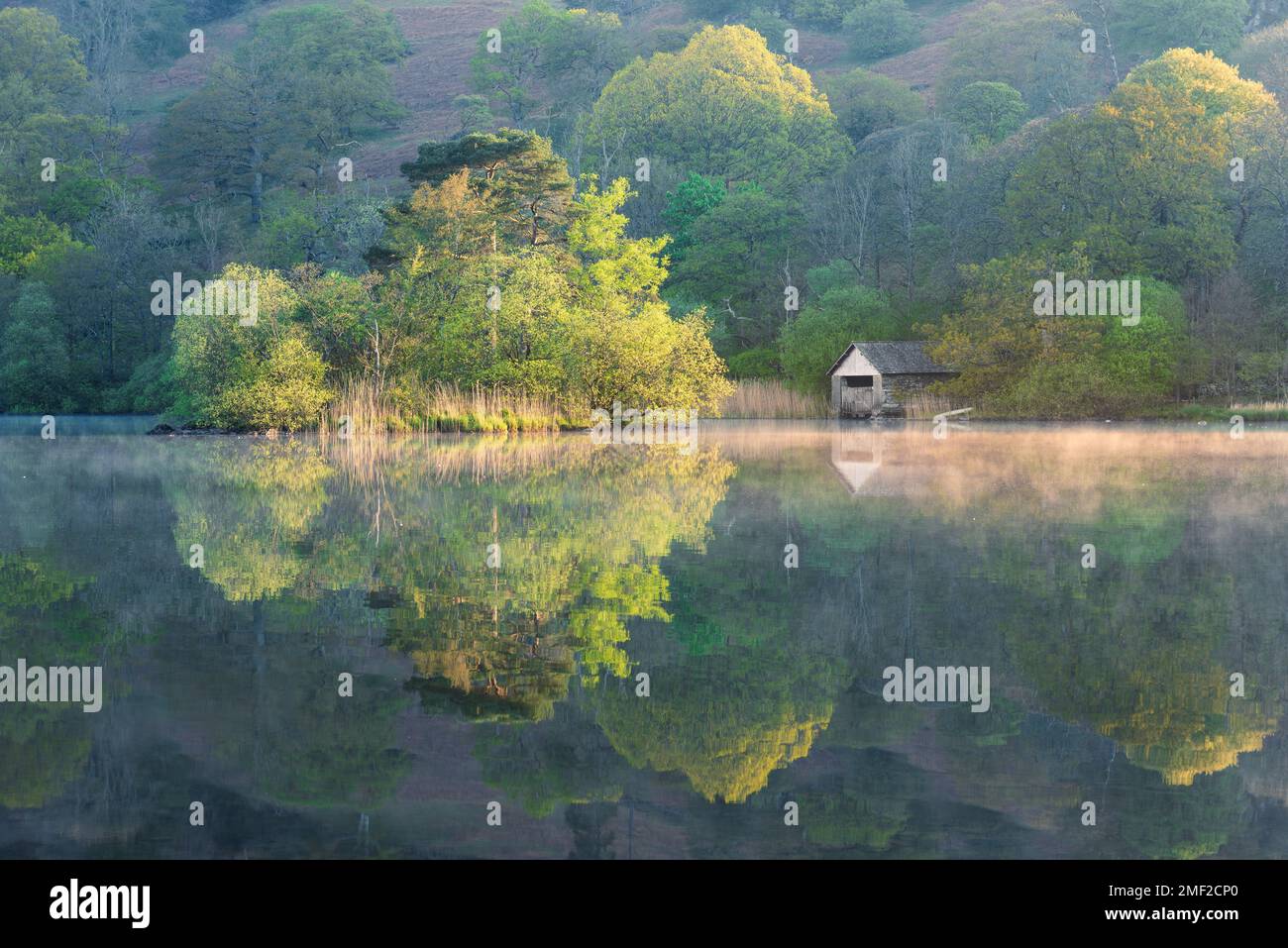 Calm reflections in lake with rustic boathouse at Rydal Water in the ...