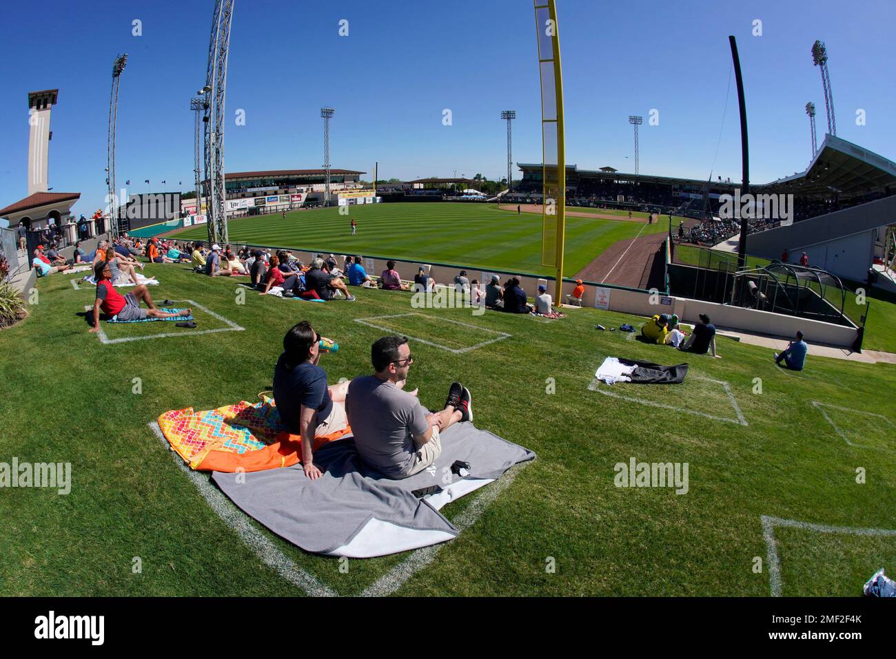 Socially distanced baseball fans sit in boxes marked in the grass on a ...