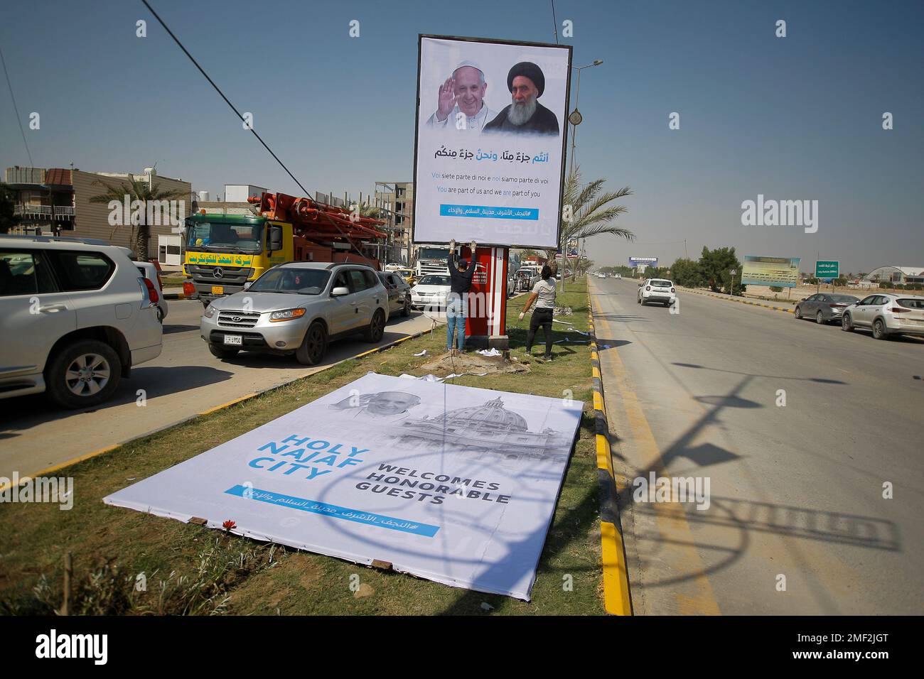 Iraqis put up a poster announcing the upcoming visit of the Pope ...