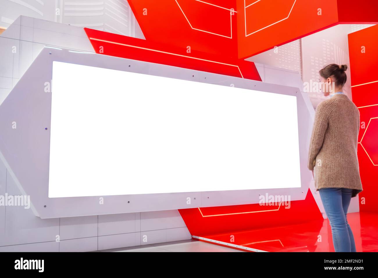 Woman looking at empty white large wall display at trade show - mockup ...