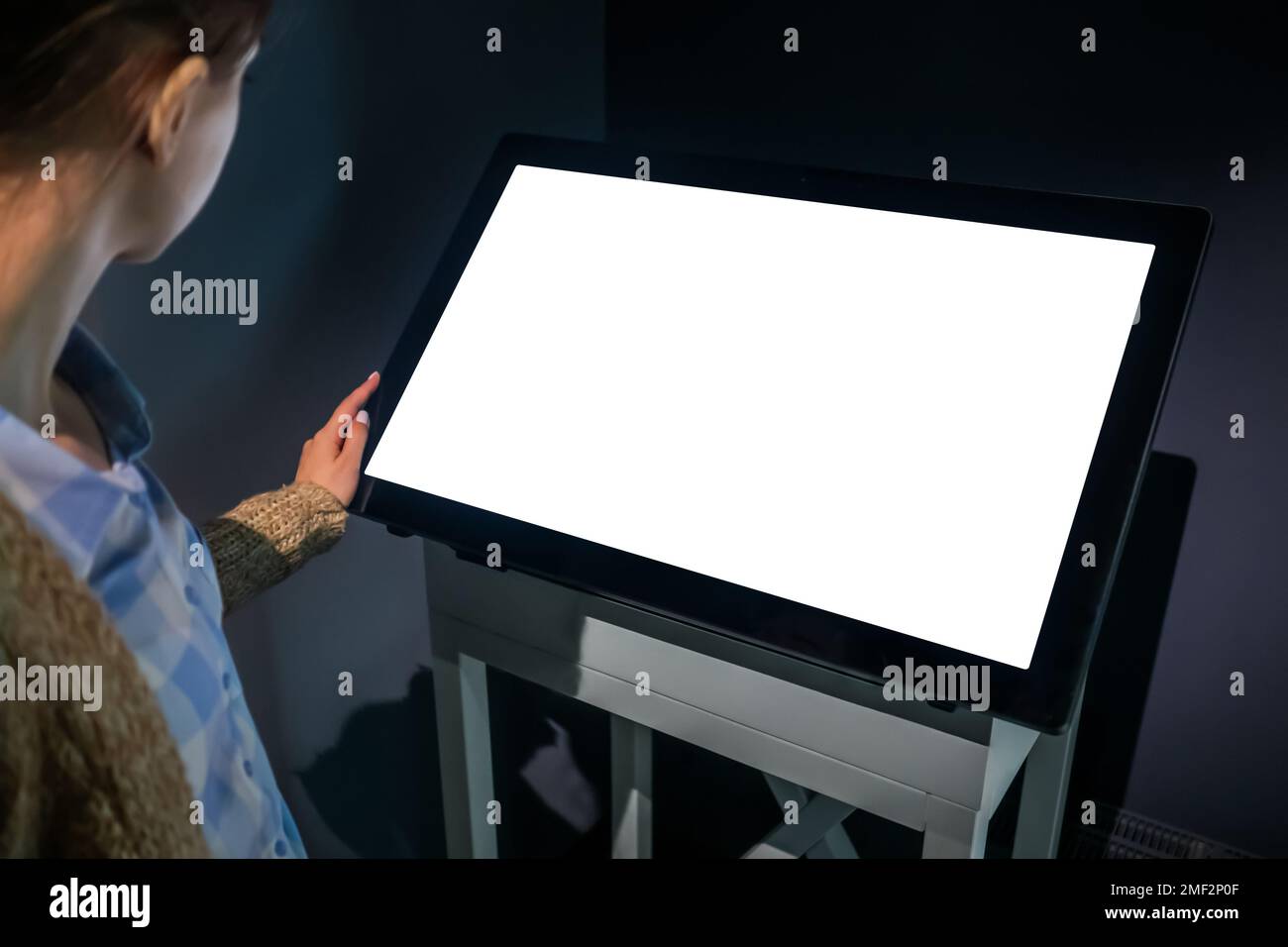 Woman using interactive empty white touchscreen display kiosk at ...