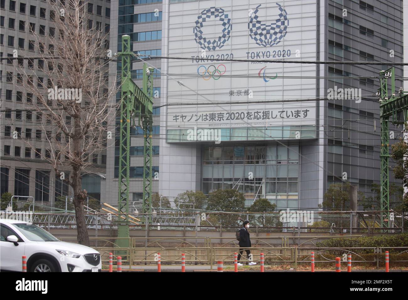 A man wearing face masks passes by the logo of the Tokyo Olympics and ...