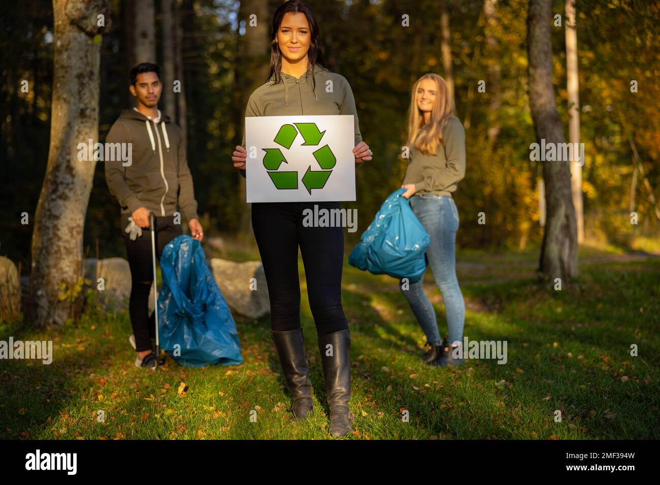 Confident volunteer woman holding recycling symbol placard in front of ...
