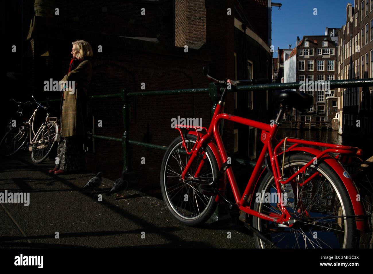 A woman enjoys the sun on a bridge connecting two alleys in the center ...