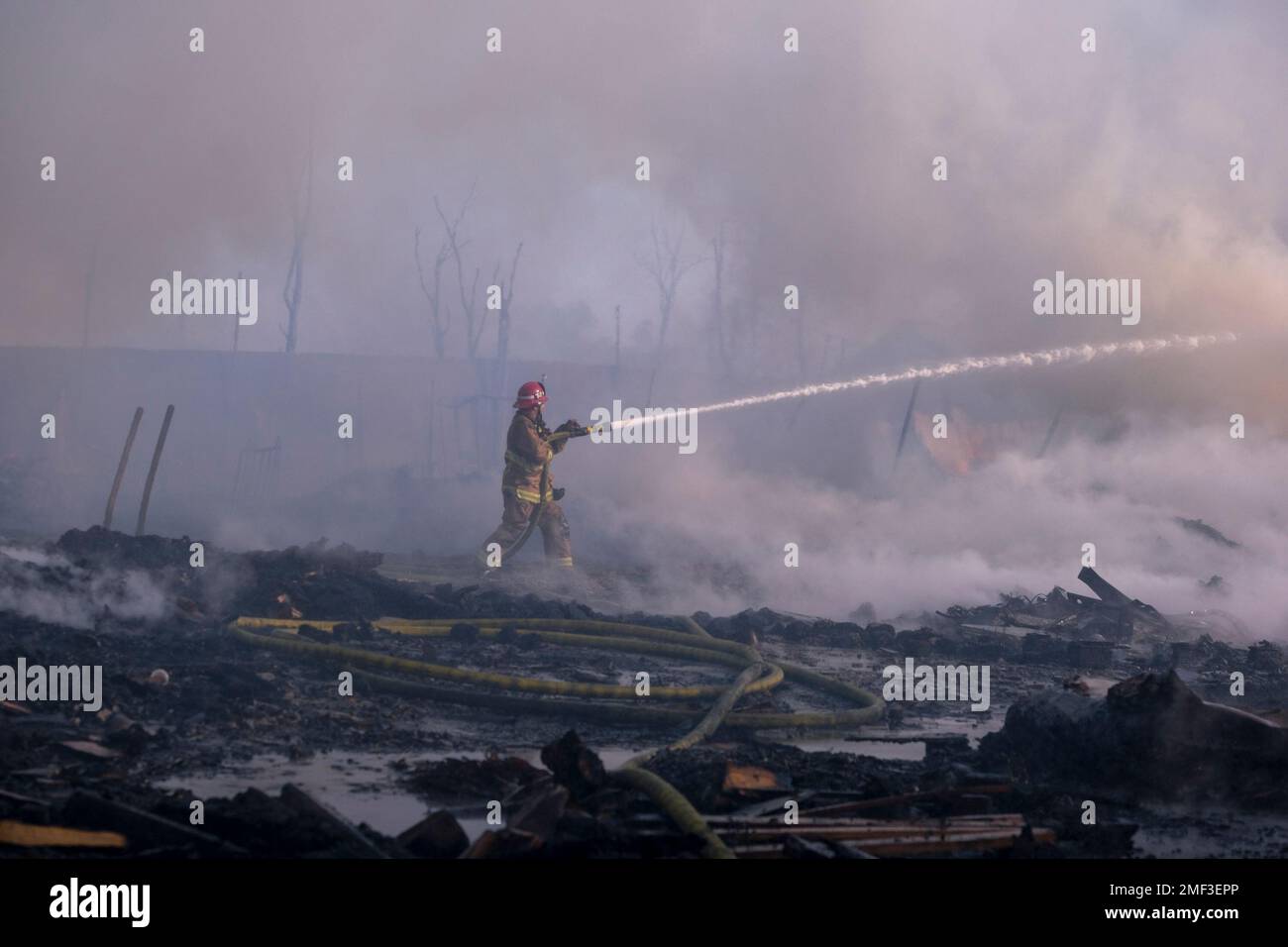 A firefighter battles a fire at a commercial yard in Compton, Calif ...
