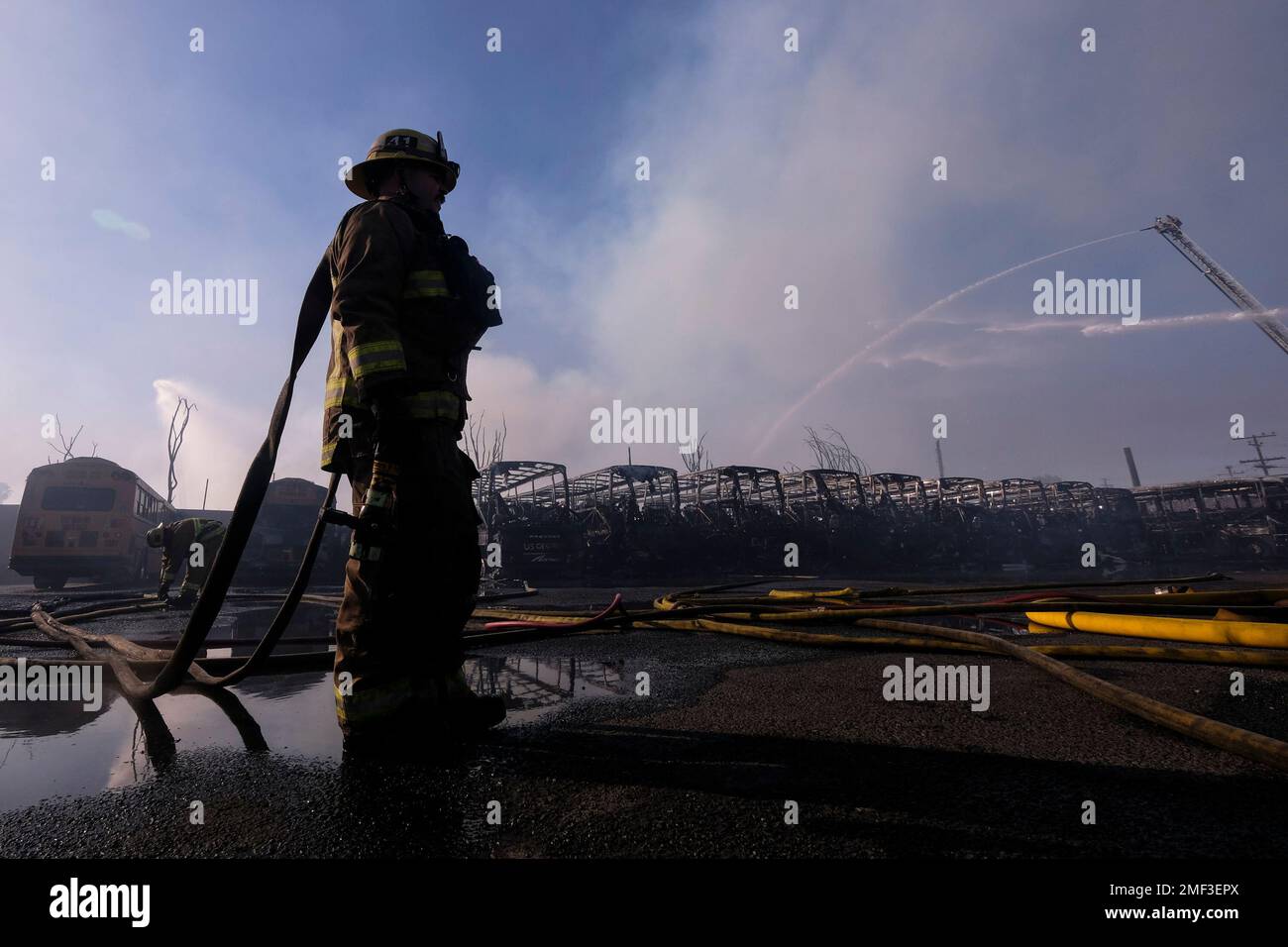 Firefighters stray water on the burned buses at a commercial yard in ...