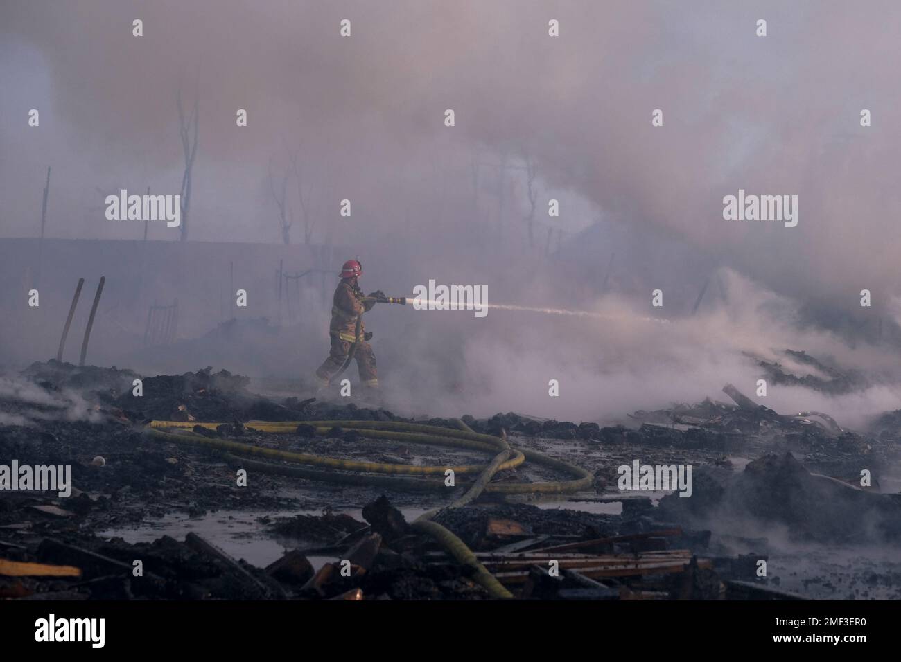 A firefighter battles a fire at a commercial yard in Compton, Calif ...