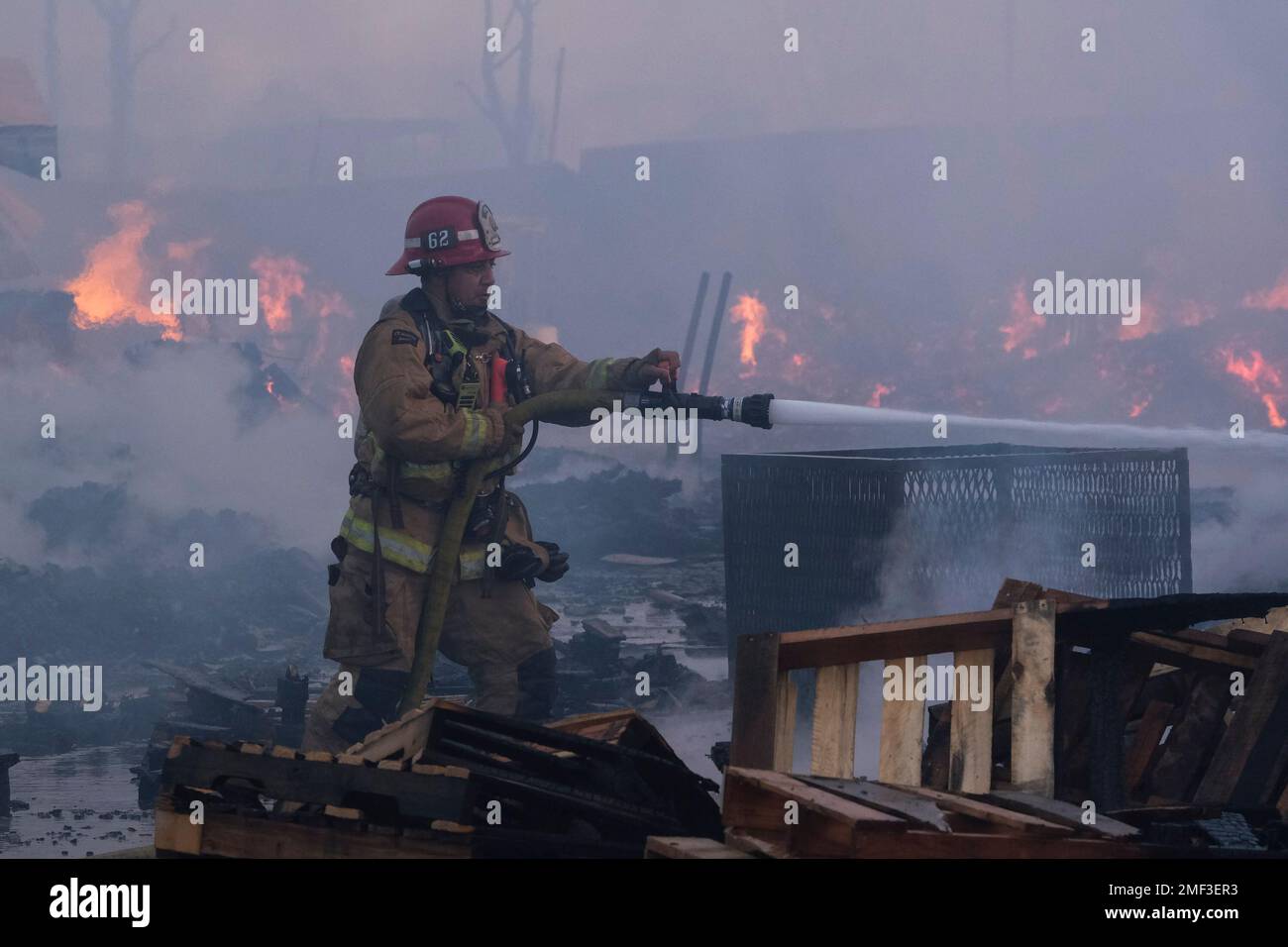 A firefighter battles a fire at a commercial yard in Compton, Calif ...