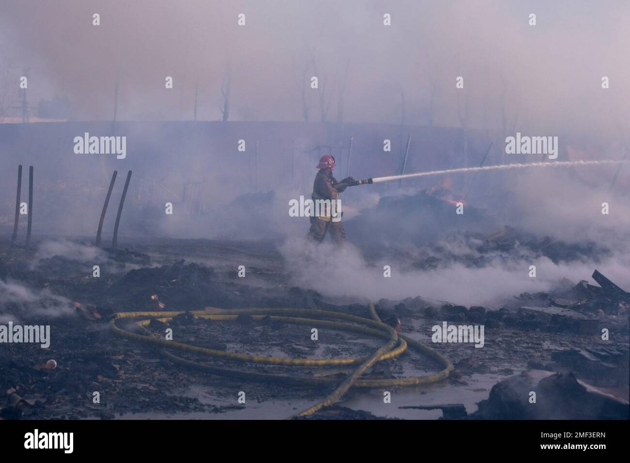 A firefighter battles a fire at a commercial yard in Compton, Calif ...