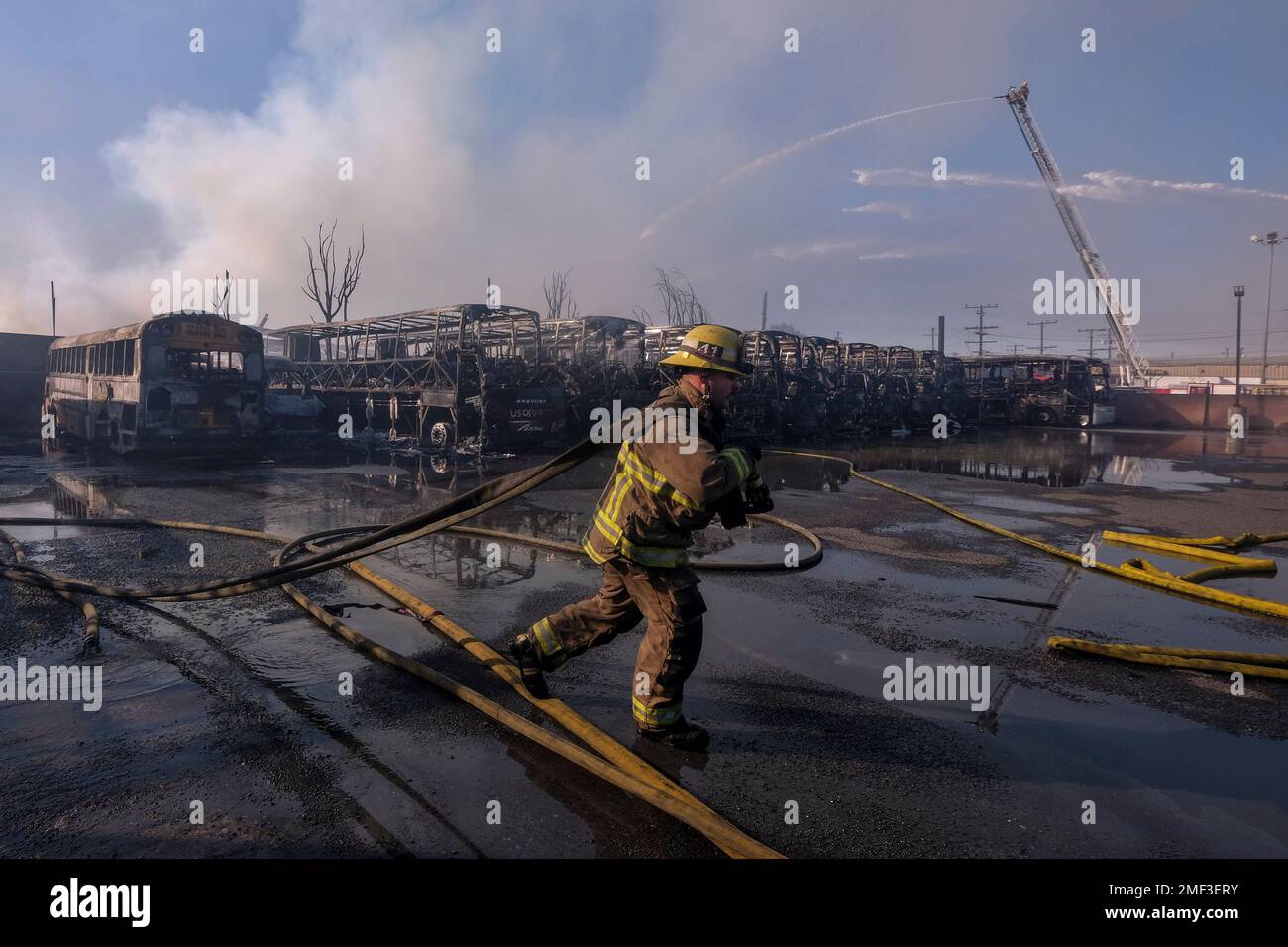 Firefighters stray water on the burned buses at a commercial yard in ...