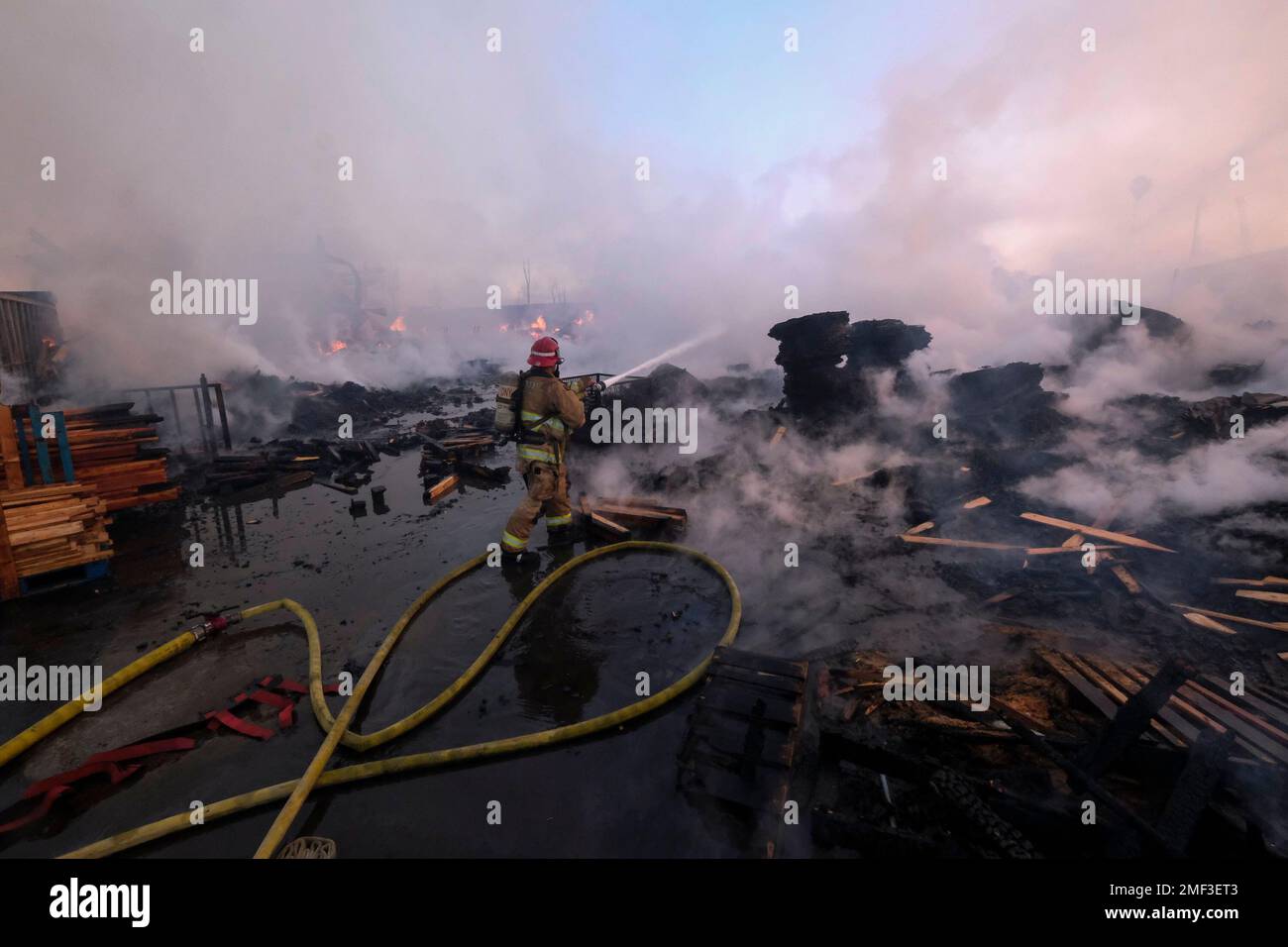 A firefighter battles a fire at a commercial yard in Compton, Calif ...
