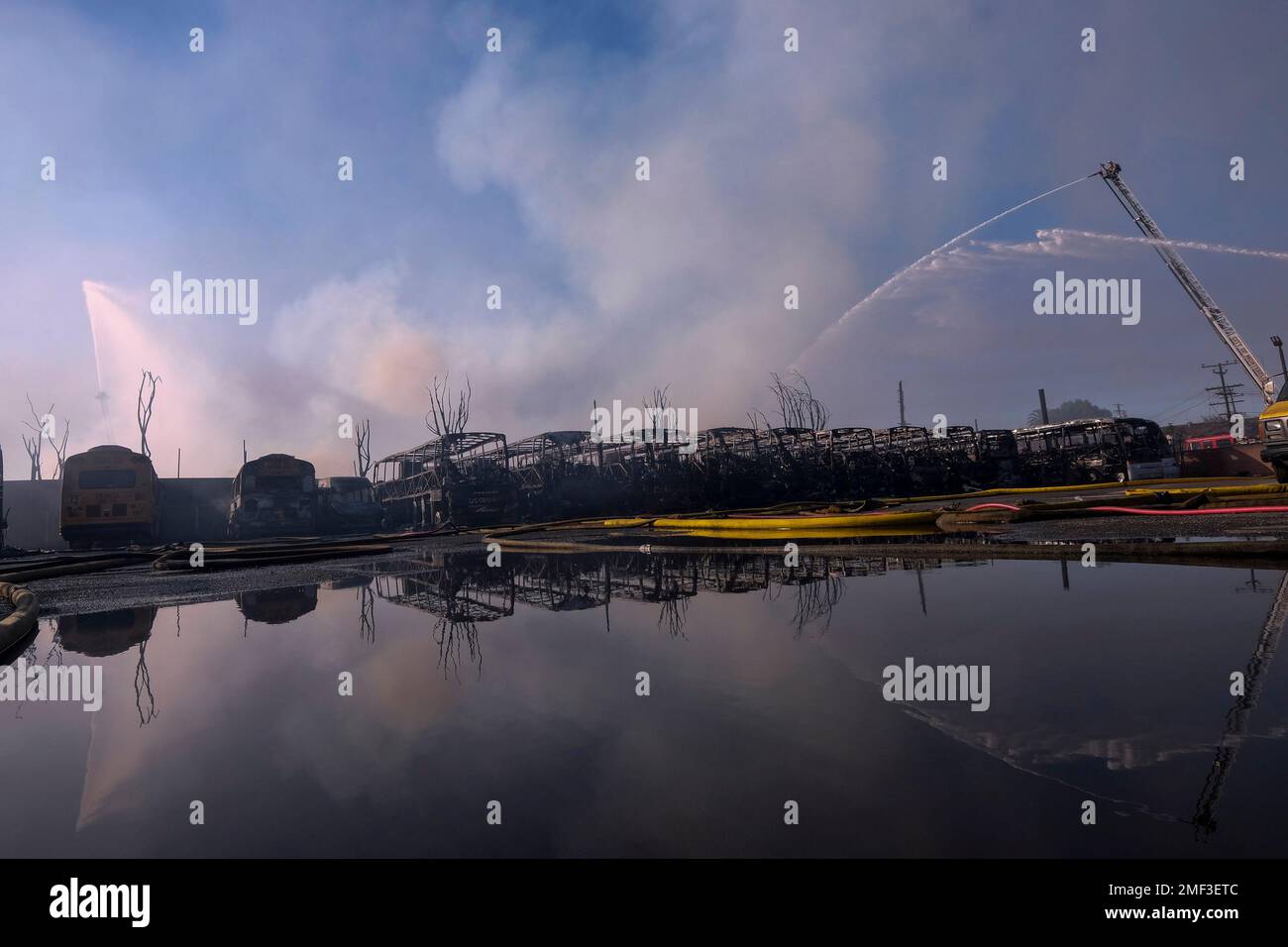 Firefighters stray water on the burned buses at a commercial yard in ...