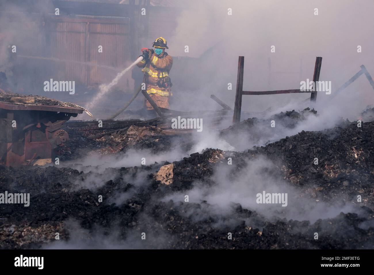 A firefighter battles a fire at a commercial yard in Compton, Calif ...