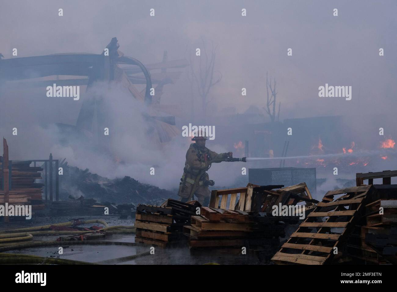A firefighter battles a fire at a commercial yard in Compton, Calif ...
