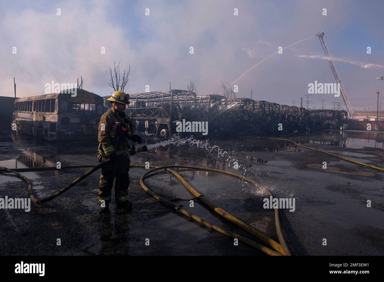 Firefighters stray water on the burned buses at a commercial yard in ...