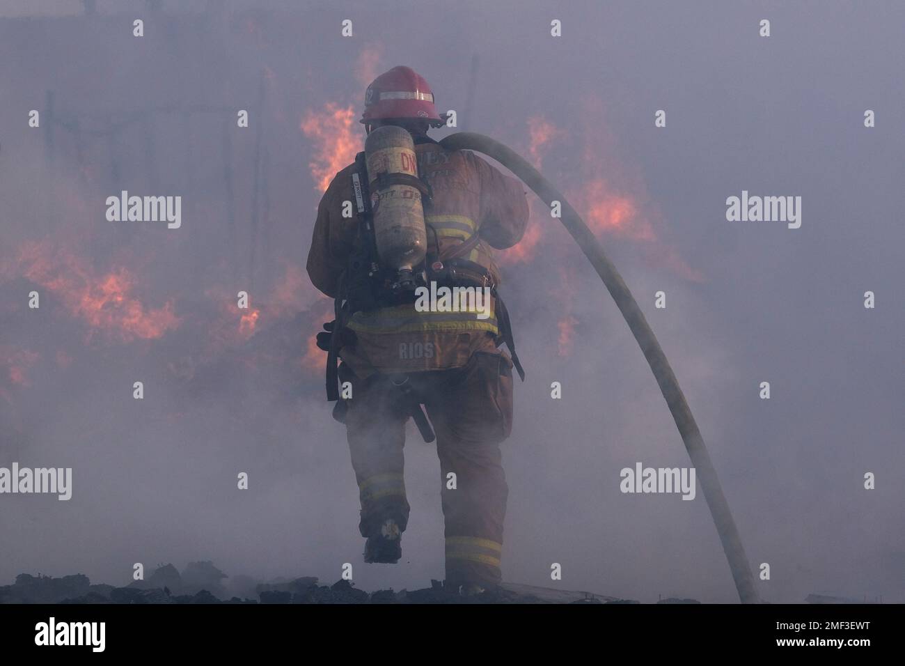 A firefighter battles a fire at a commercial yard in Compton, Calif ...