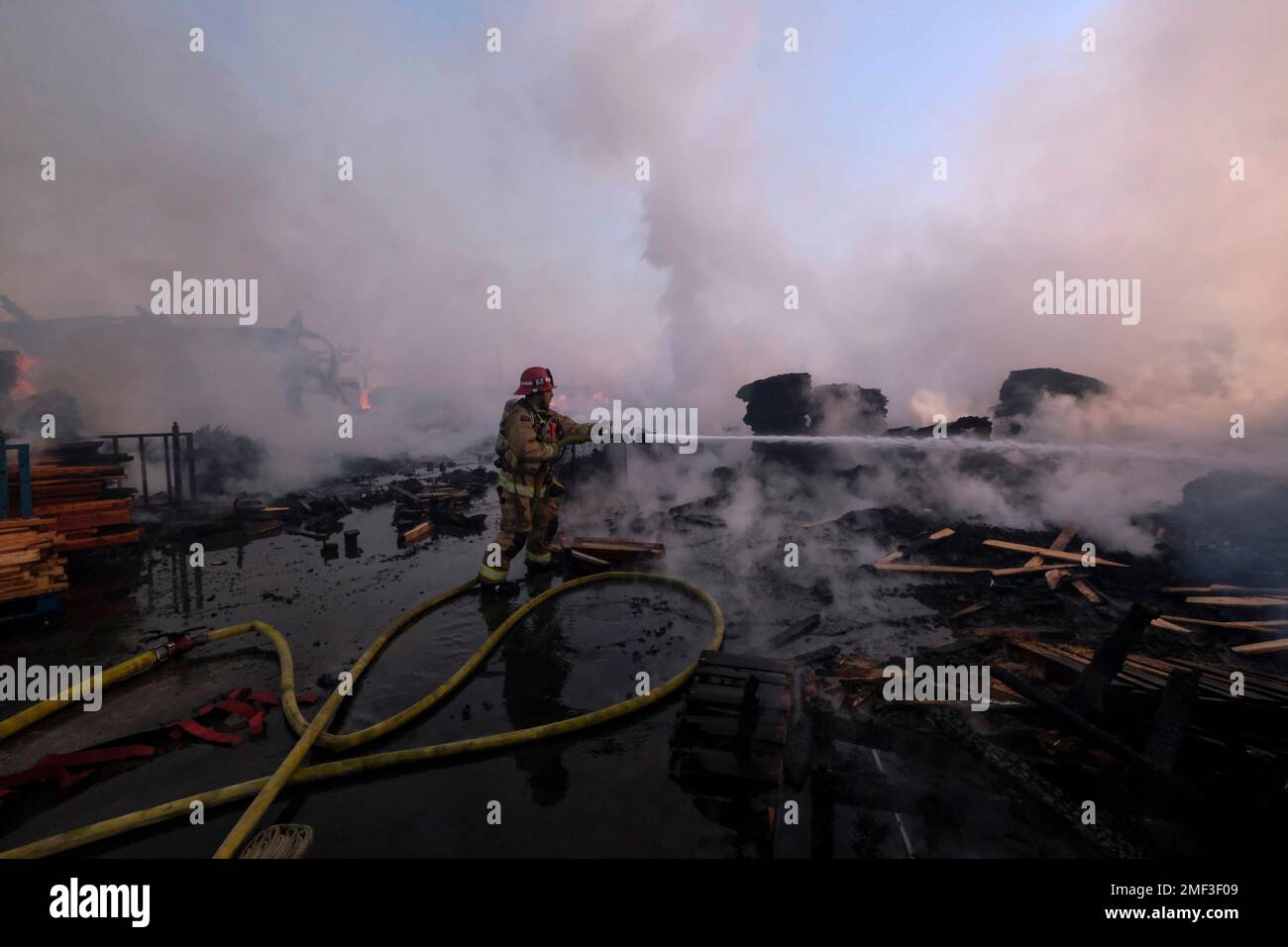 A firefighter battles a fire at a commercial yard in Compton, Calif ...