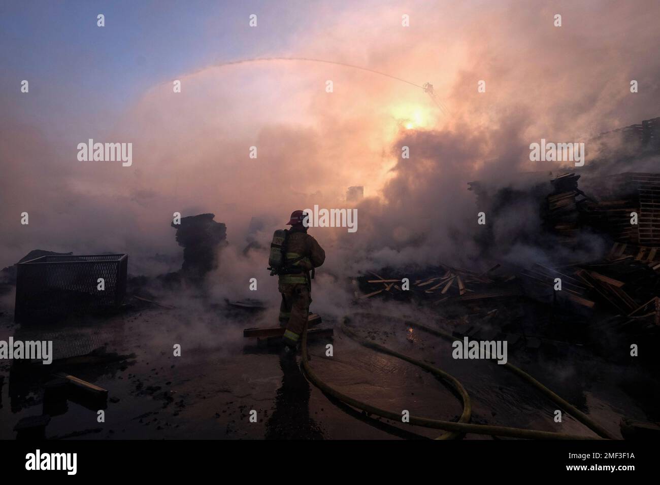 A firefighter battles a fire at a commercial yard in Compton, Calif ...