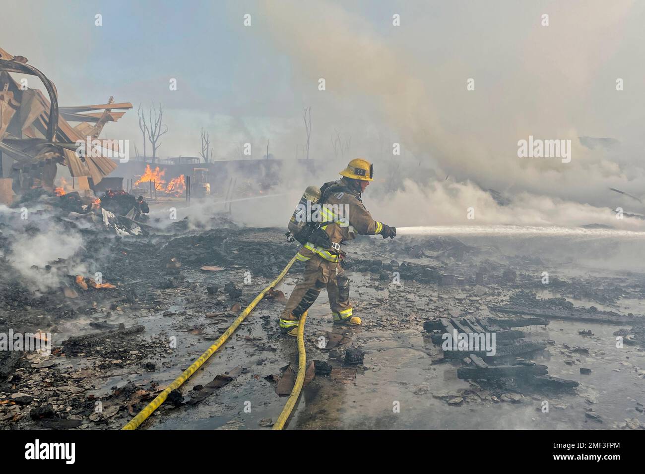 A firefighter battles a fire at at commercial yard in Compton, Calif ...