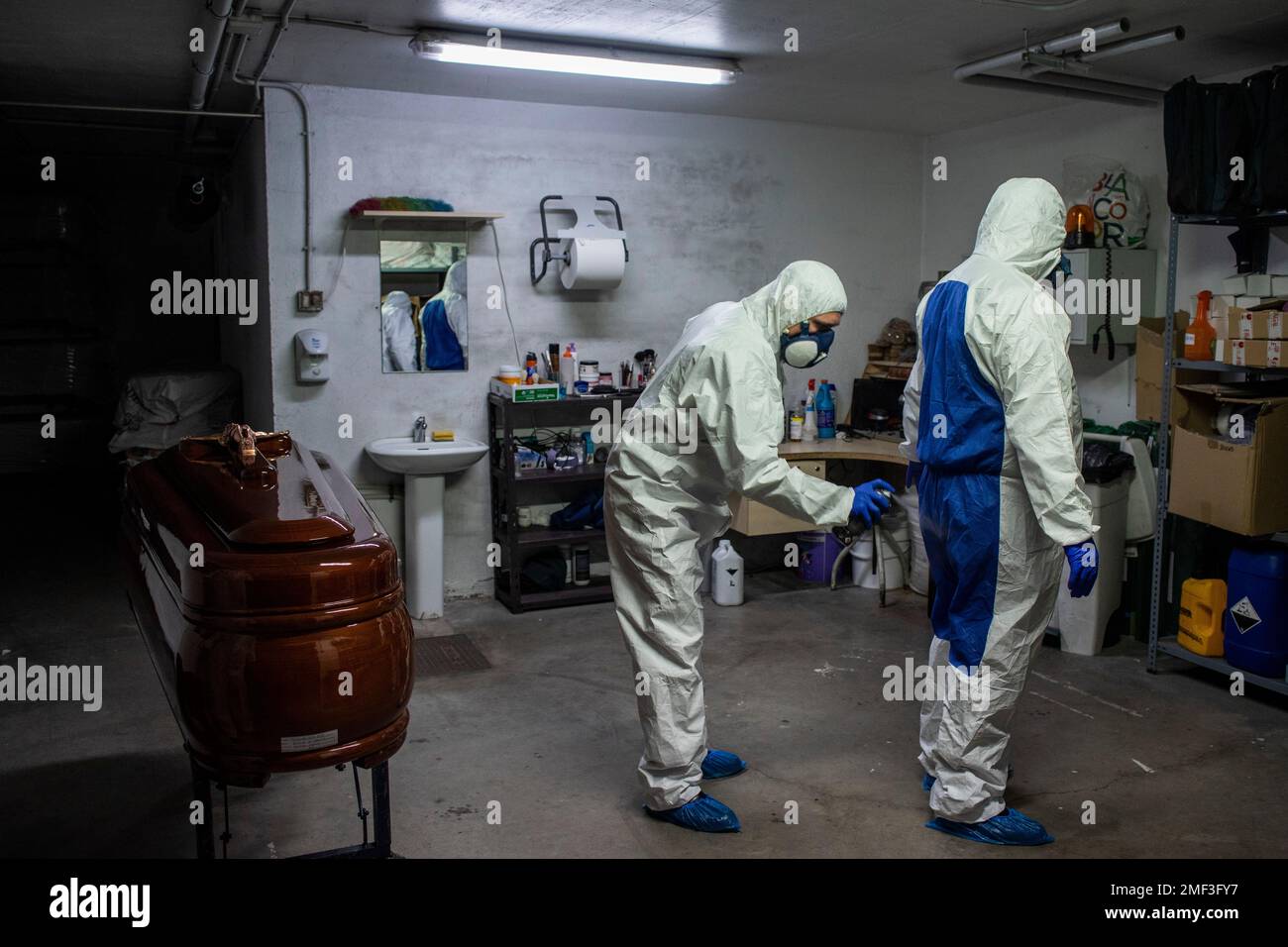 A funeral employee disinfects a coworker after manipulating the coffin ...