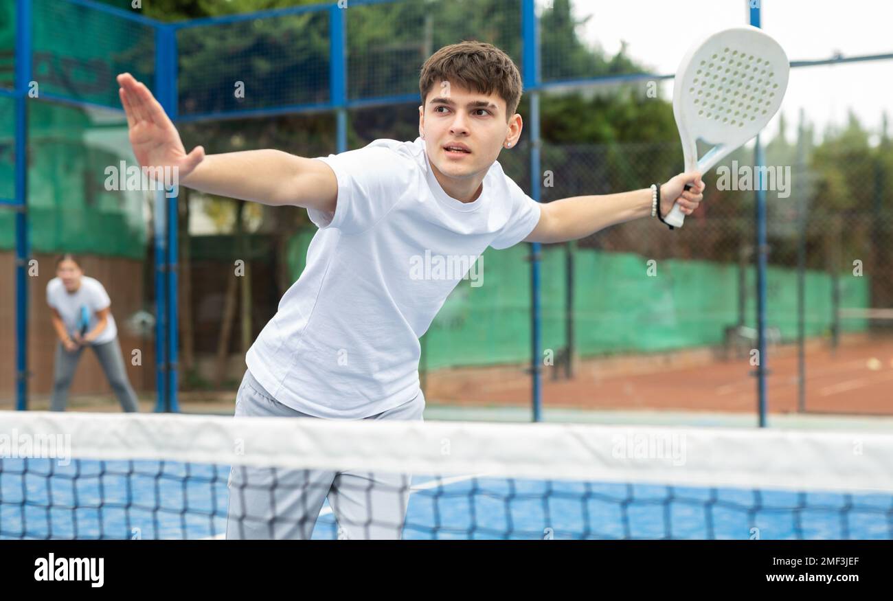 Sportive young man holding padel racquet in hand and ready to return ...