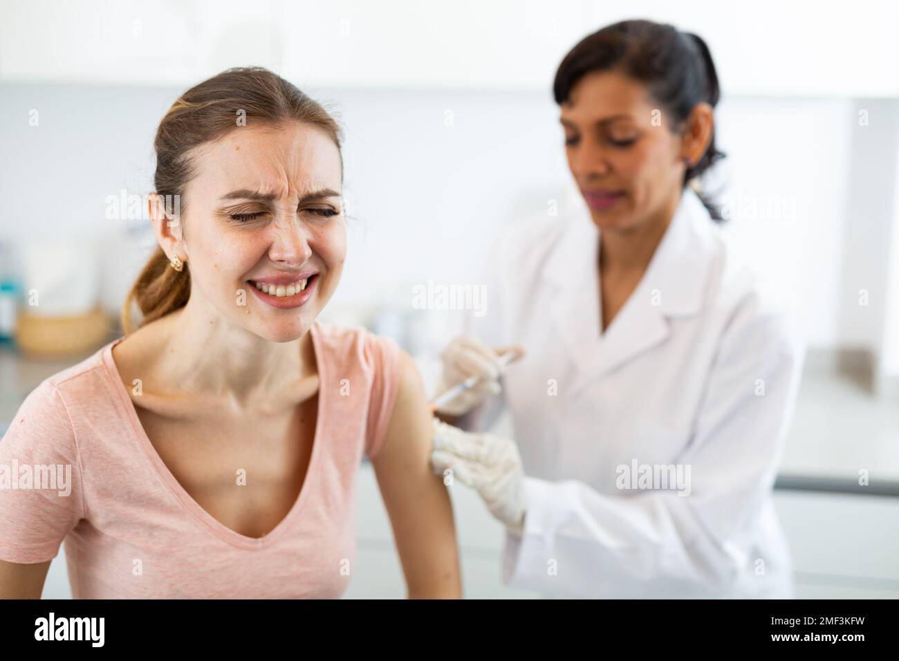 Scared woman getting injection at doctors office Stock Photo - Alamy