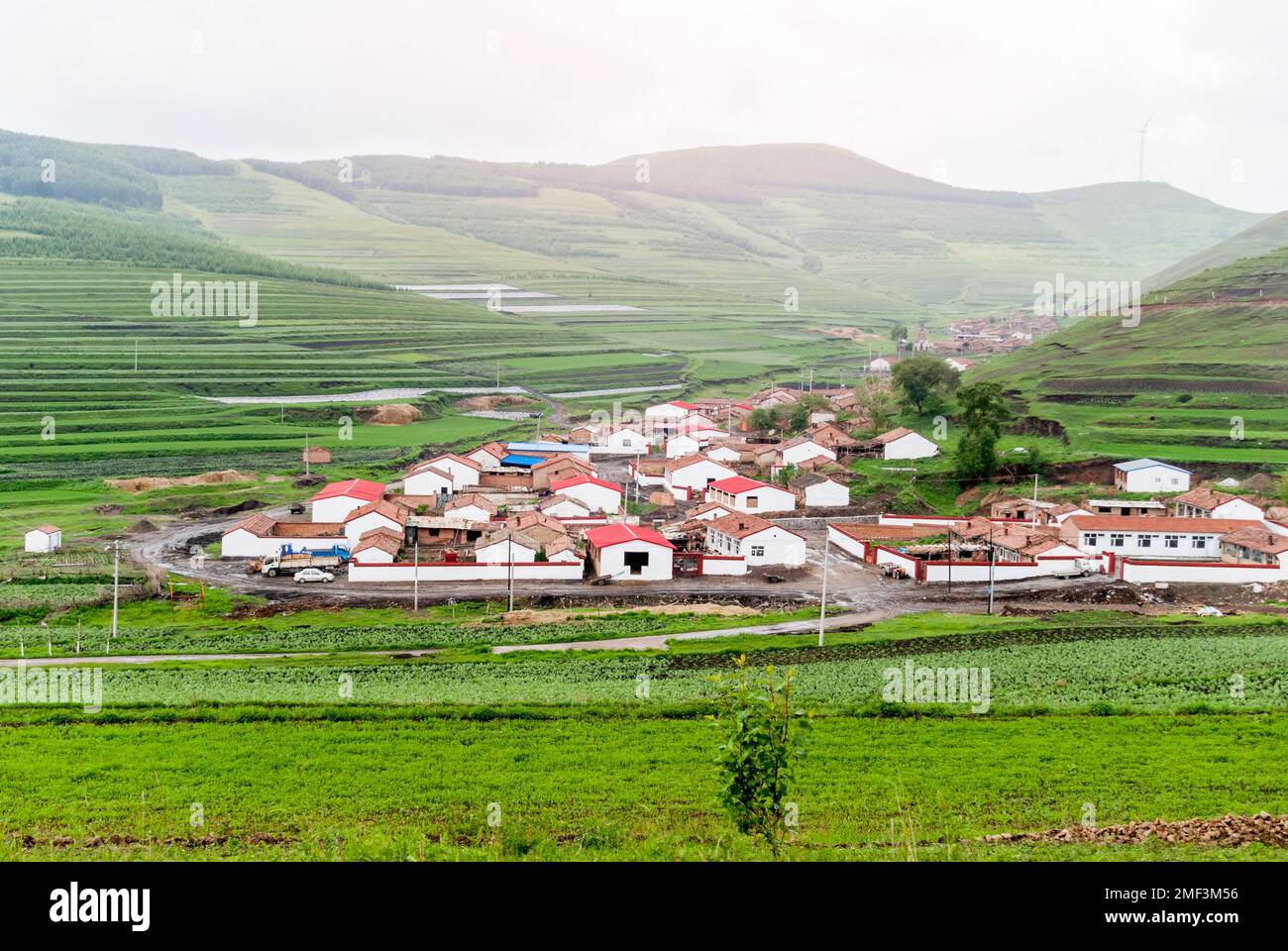 A high angle closeup shot of houses on a grass field with a mountain ...