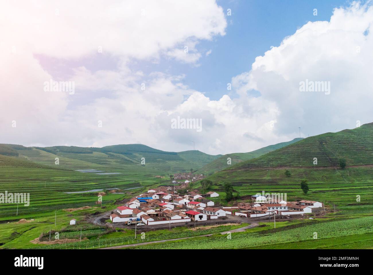 A high angle closeup shot of houses on a grass field with a mountain ...