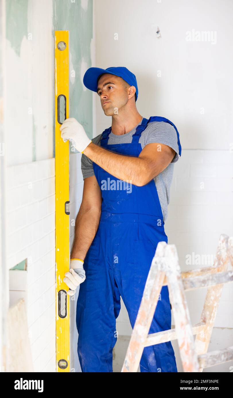Professional man builder in work clothes holding level in hands and ...