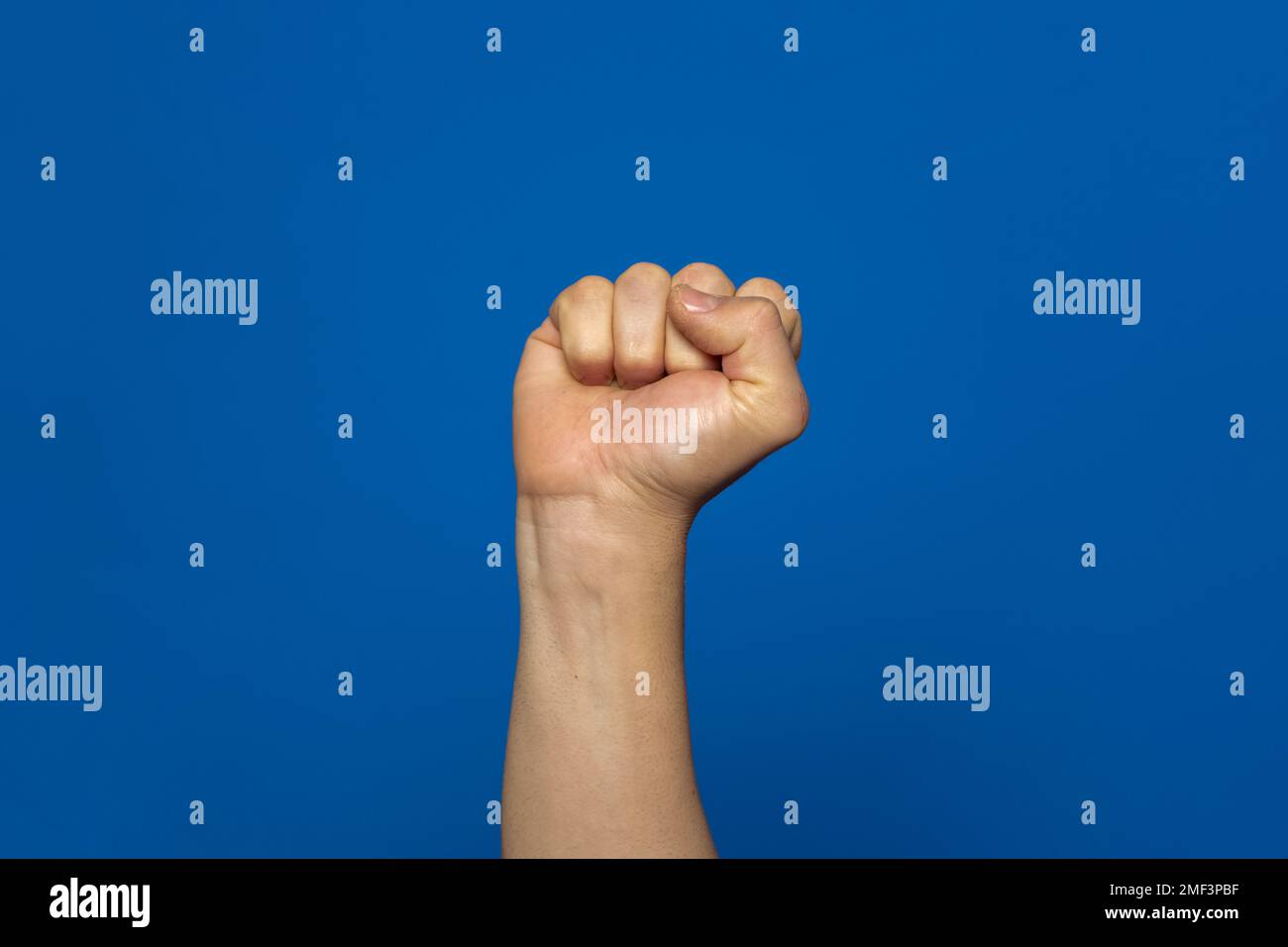 Man's fist seized with power isolated on blue background. Symbol of ...