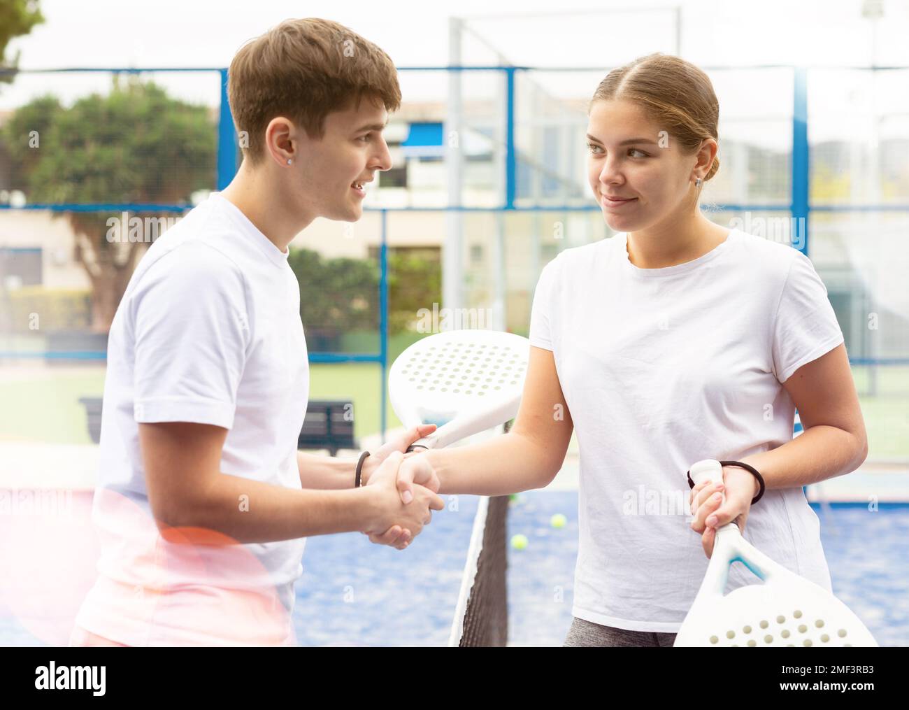 Young man and woman shake hands after playing padel on tennis court ...