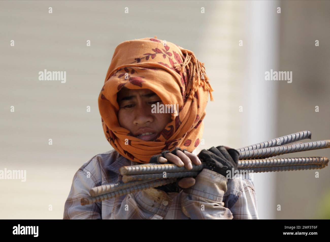 A female worker carries steel materials for building a new road at a ...