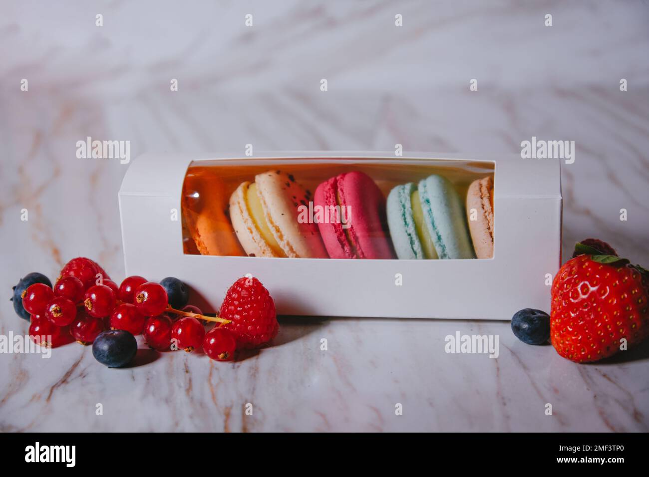 Macaron dessert, a box with colorful macarons lies on a marble style ...