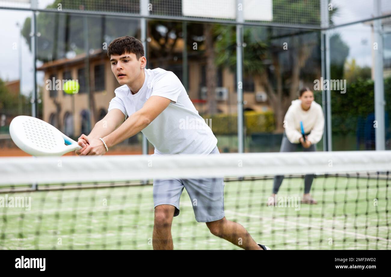 Guy hitting two handed backhand during paddle tennis match Stock Photo - Alamy