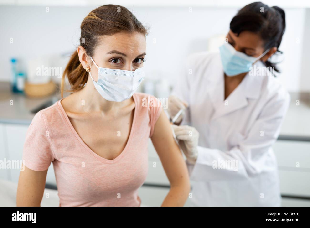 Confident female doctor making injection to woman Stock Photo - Alamy