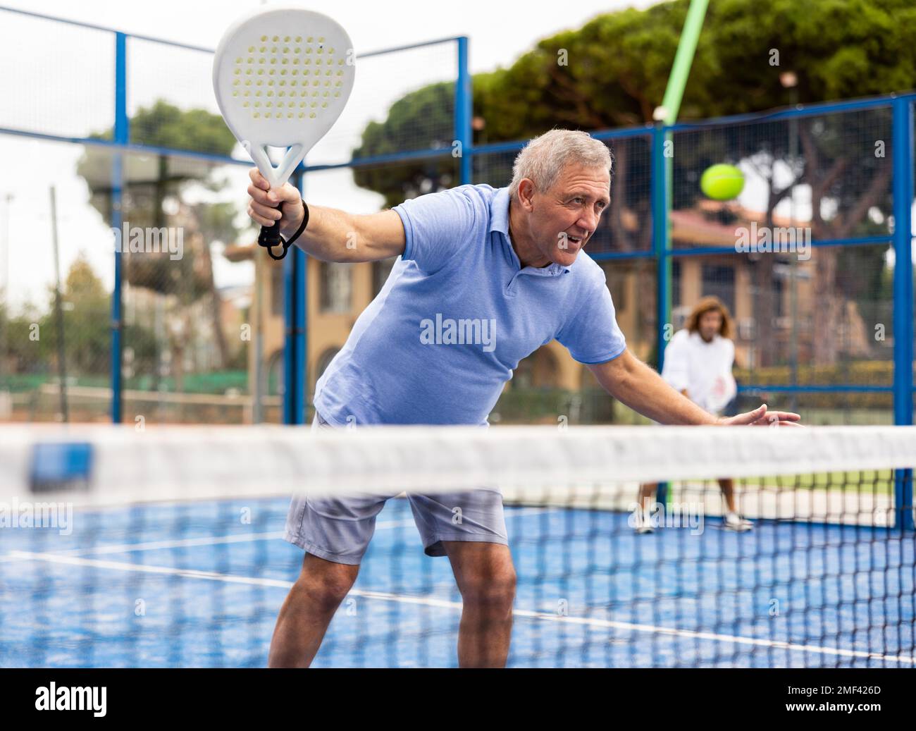 Emotional mature male playing padel behind the net during match on ...