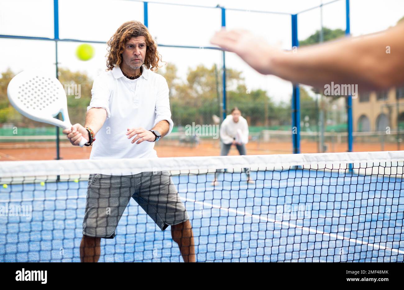 Serious middle-aged Latin man tennis player playing padel during ...