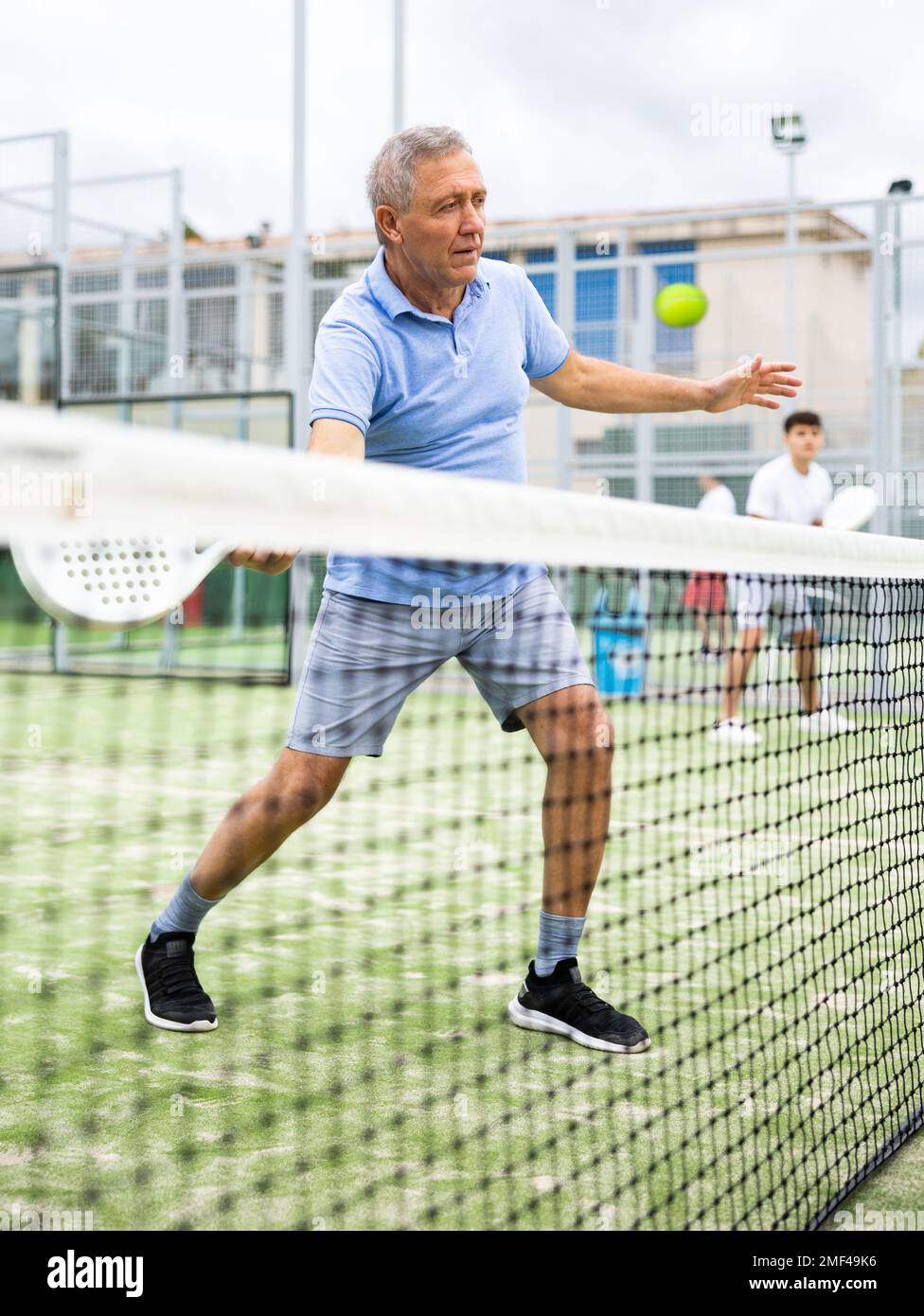 Sporty senior man playing padel on open tennis court Stock Photo - Alamy