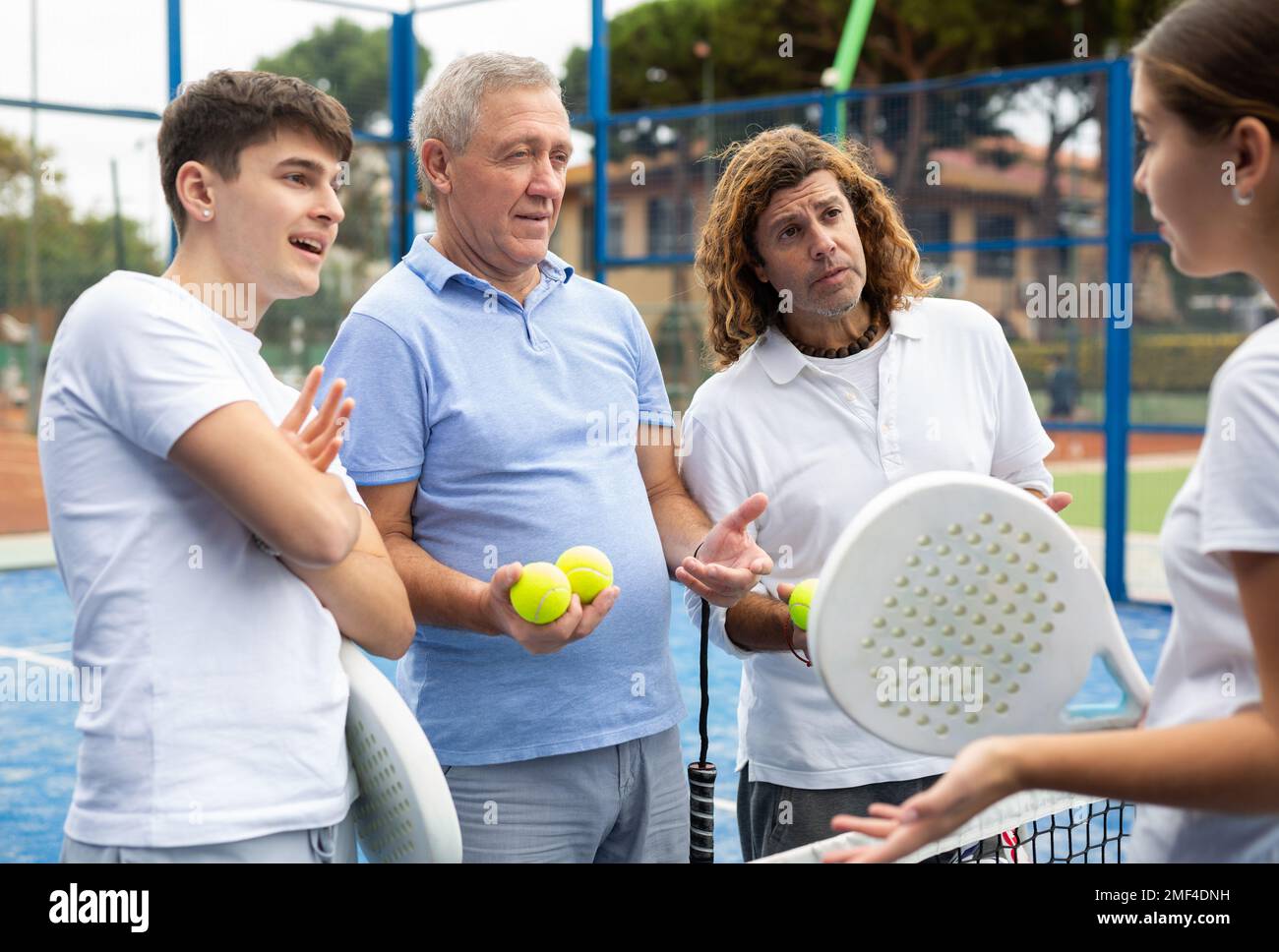 Happy people with rackets for padel talking on court Stock Photo - Alamy