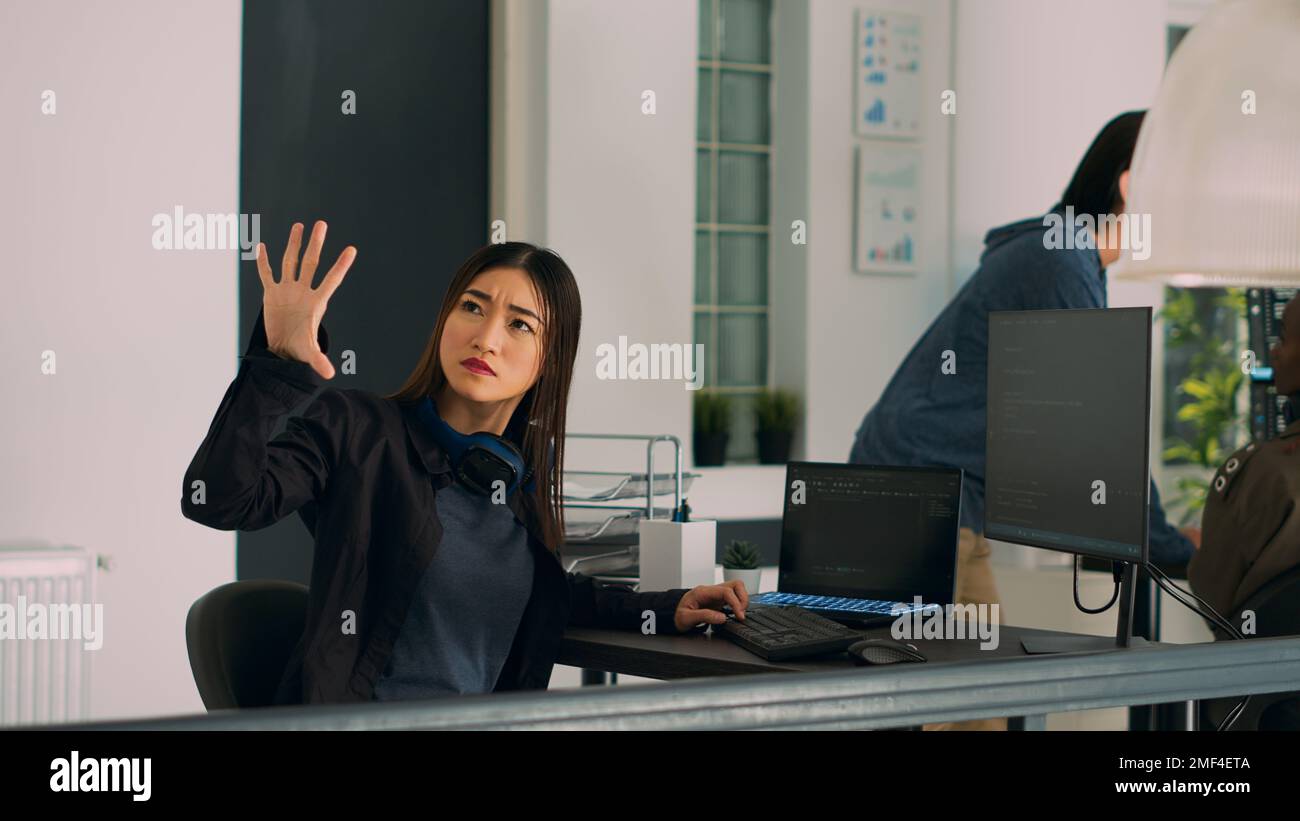 IT engineer using computer and turning head to use source code hologram, typing server ...