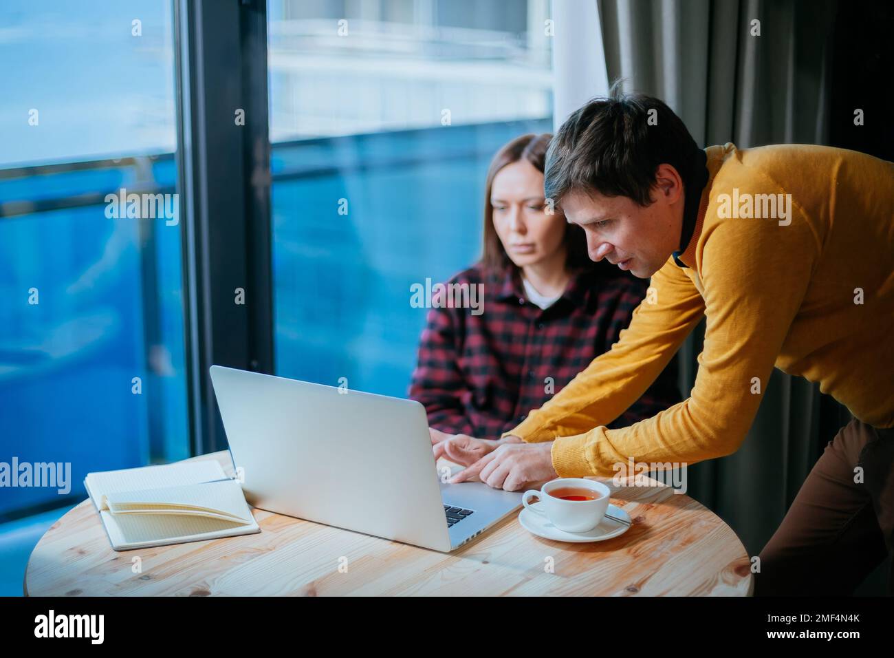 Male and female IT freelancers working with laptop and discussing ...