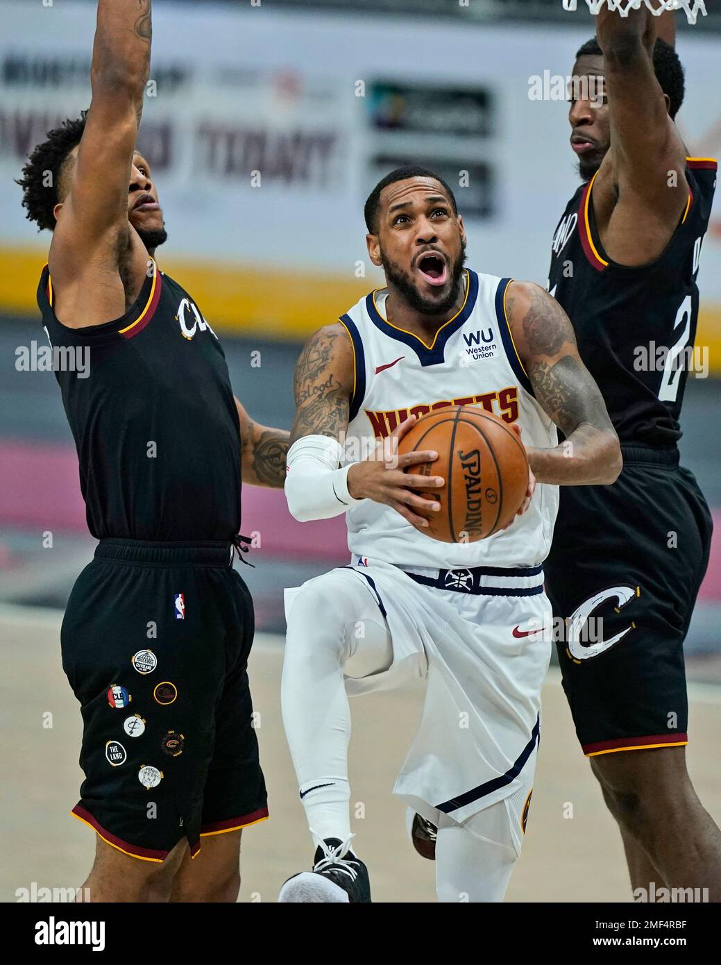 Denver Nuggets' Monte Morris, center, drives past Cleveland Cavaliers ...